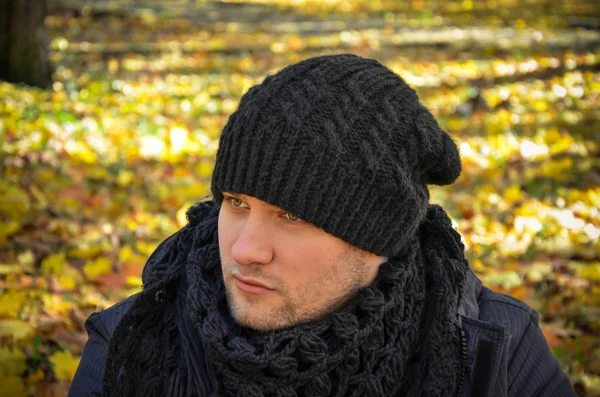 Young man with a sad look with bright autumn leaves on a backgro ...