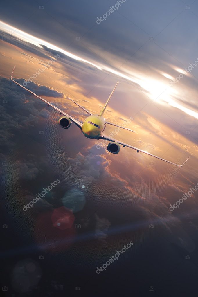 Airplane flying through beautiful clouds at the sunset time with ...