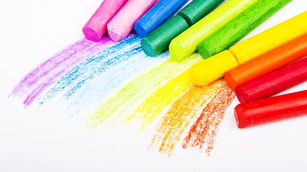Oil pastel crayons lying on a paper with painted rainbow — Stock Photo ...