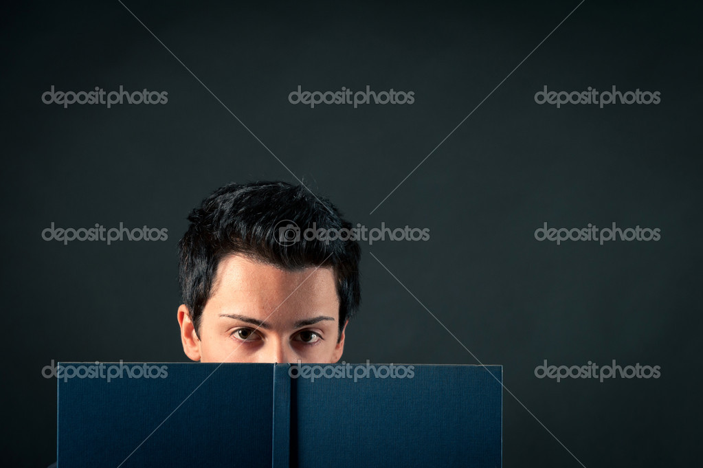 Young man behind a book against dark background Stock Photo by ©pio3 ...