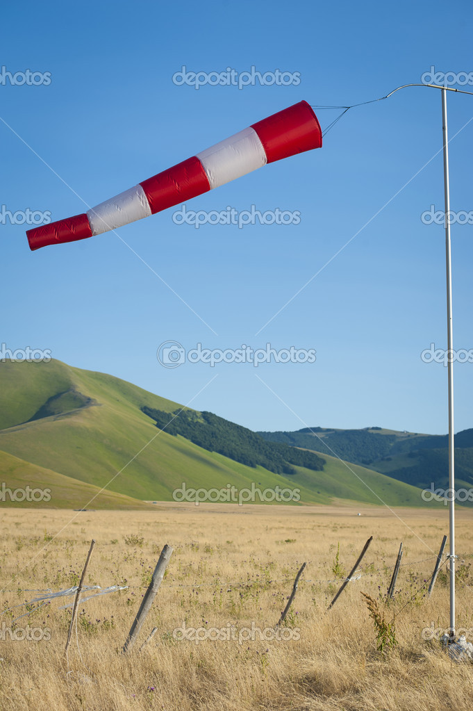 Red and white windsock blows against a blue sky. Castelluccio di Norcia ...