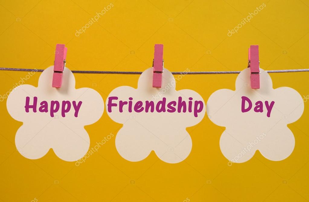Happy Friendship Day message greeting across white flower tags hanging ...