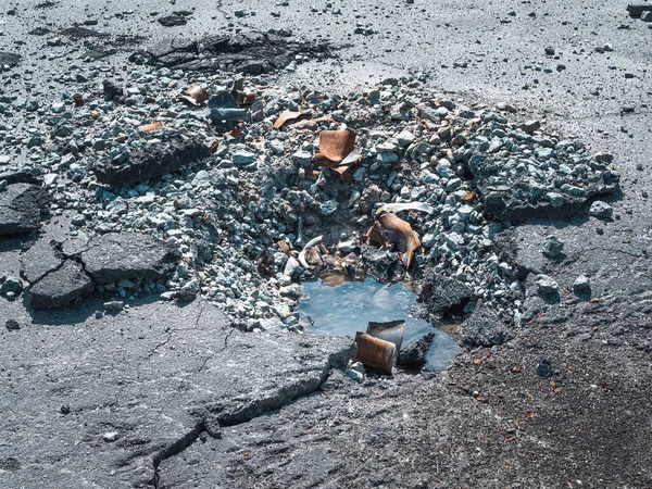 War in Ukraine, a crater in the asphalt from a shell, water comes out ...