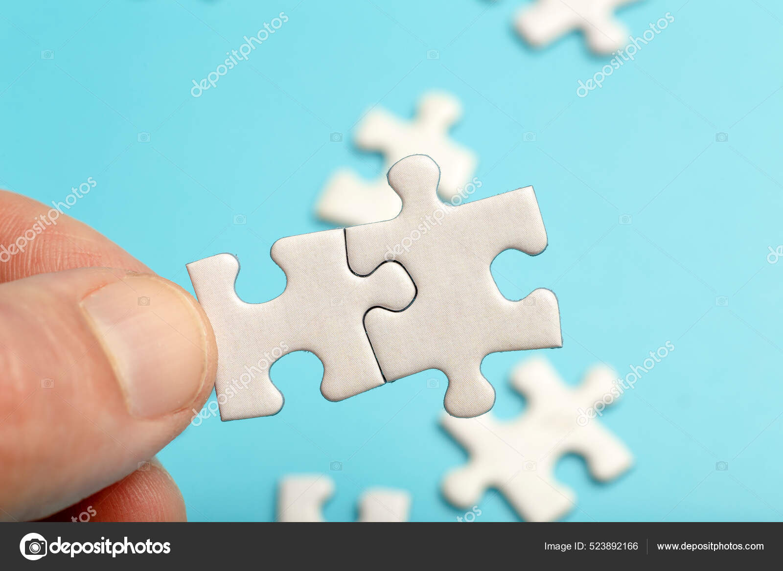 Puzzle pieces are connected. White puzzle pieces in hand on a blue ...