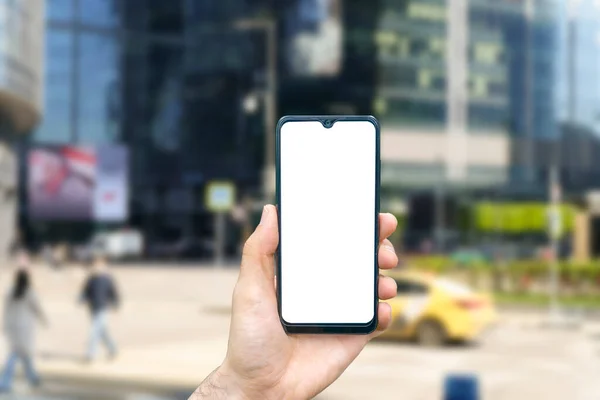 A smartphone in a hand with a blank screen against the backdrop of an ...