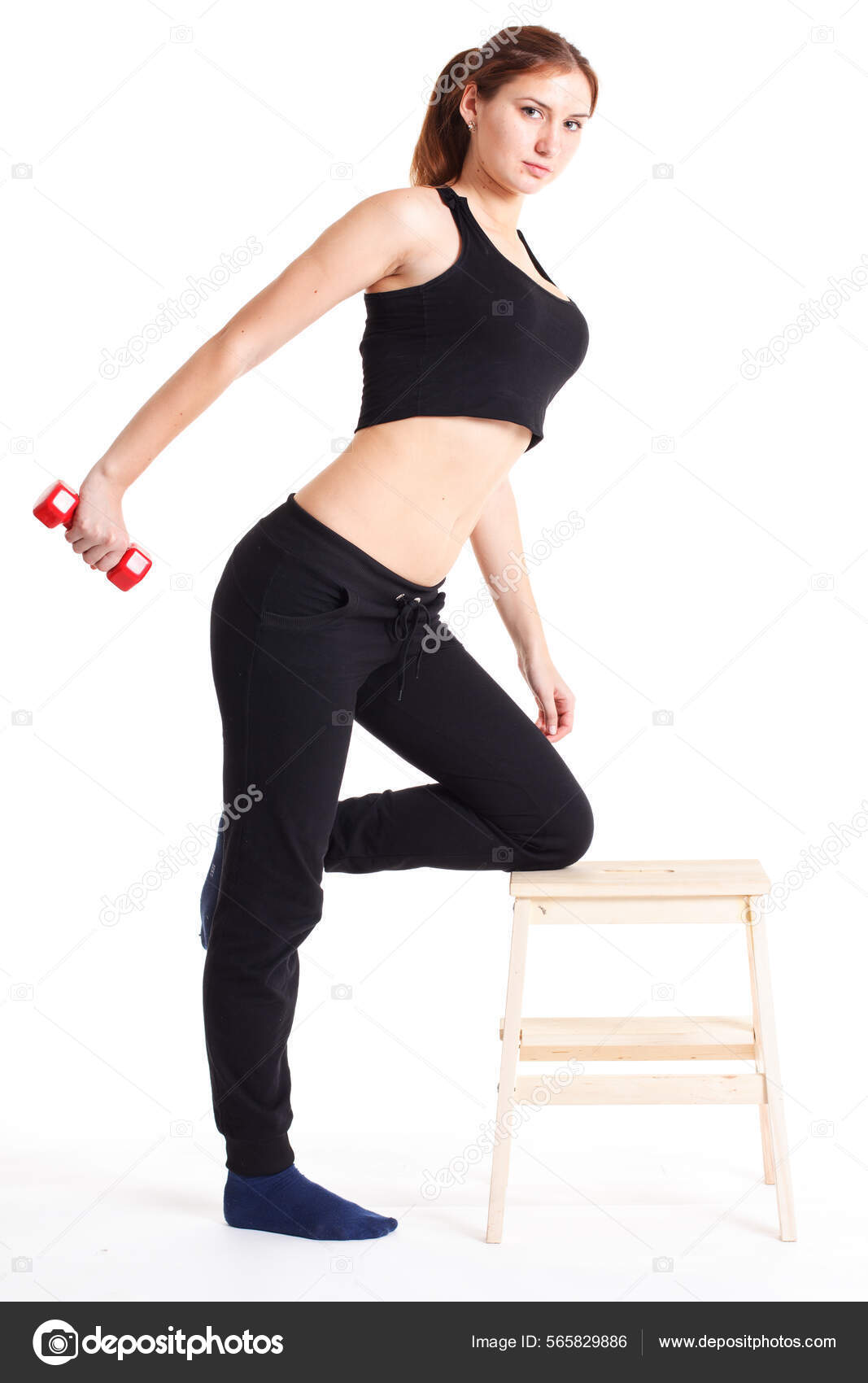 Female fitness model excercising in studio with dunbell weights and ...