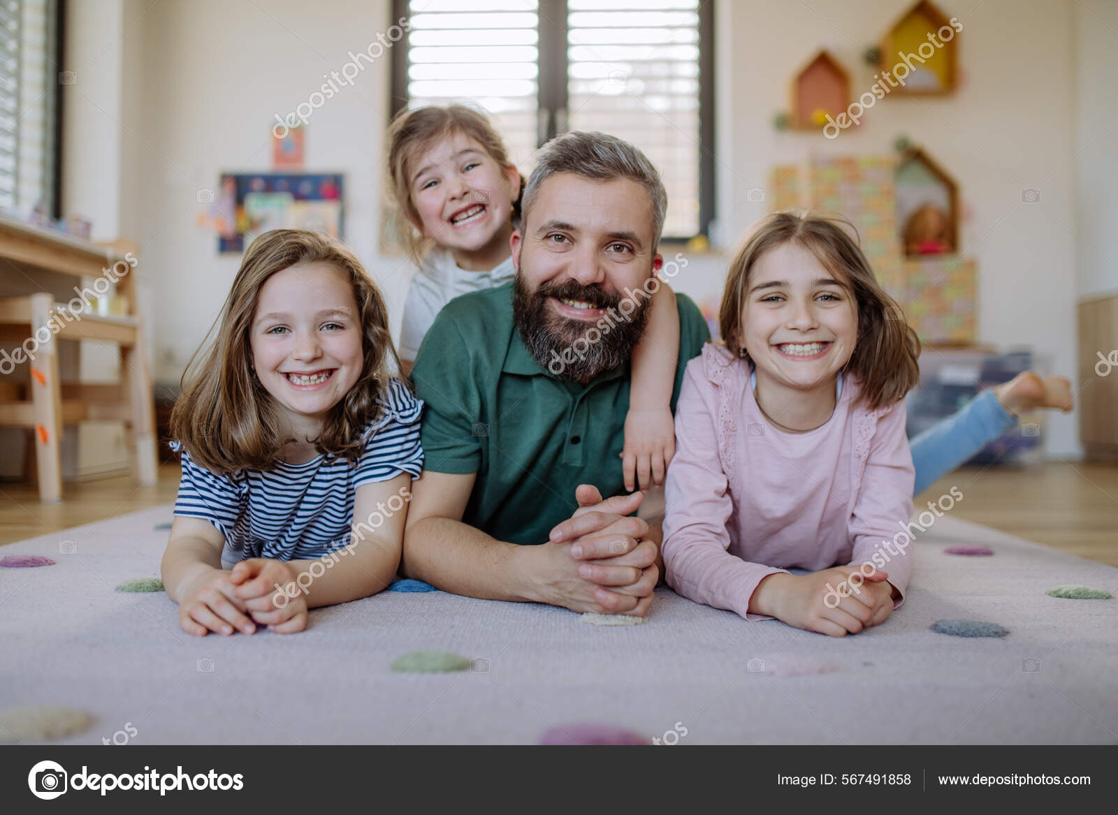 Cheerful father with three little daughters playing together at home ...