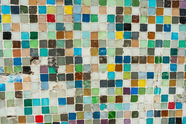 old colored mosaic on the wall. small colored squares of stone on the ...