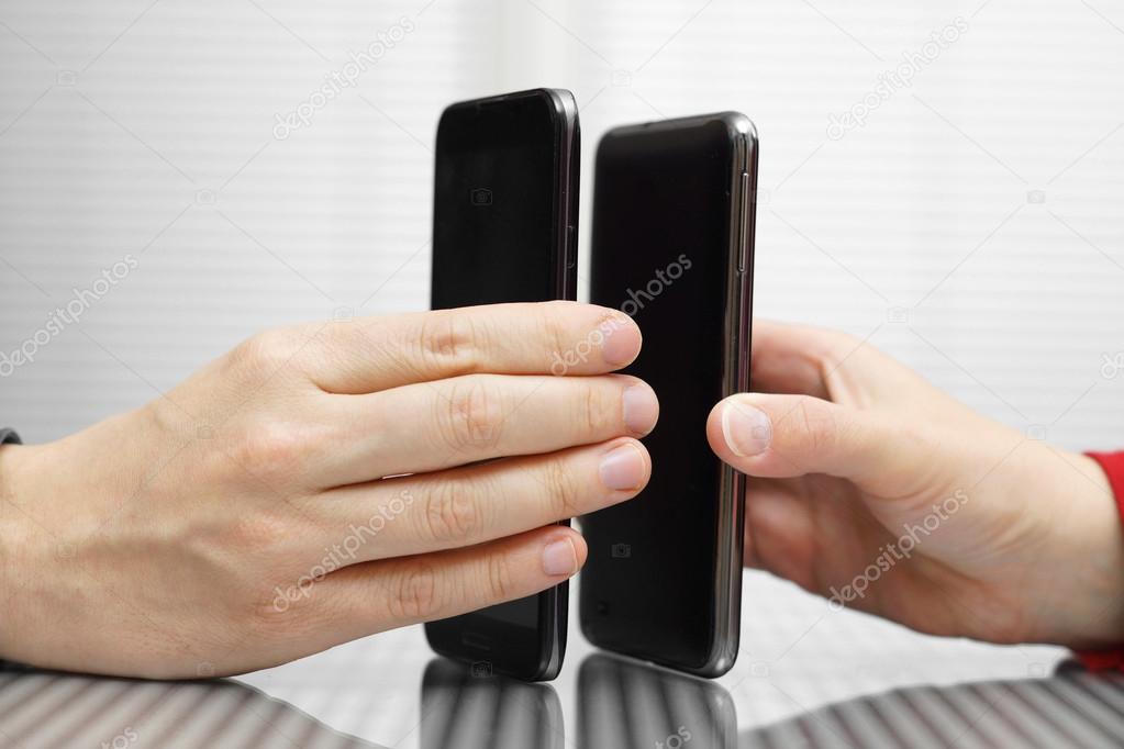 Two hands holding mobile smart phones while transferring data — Stock ...