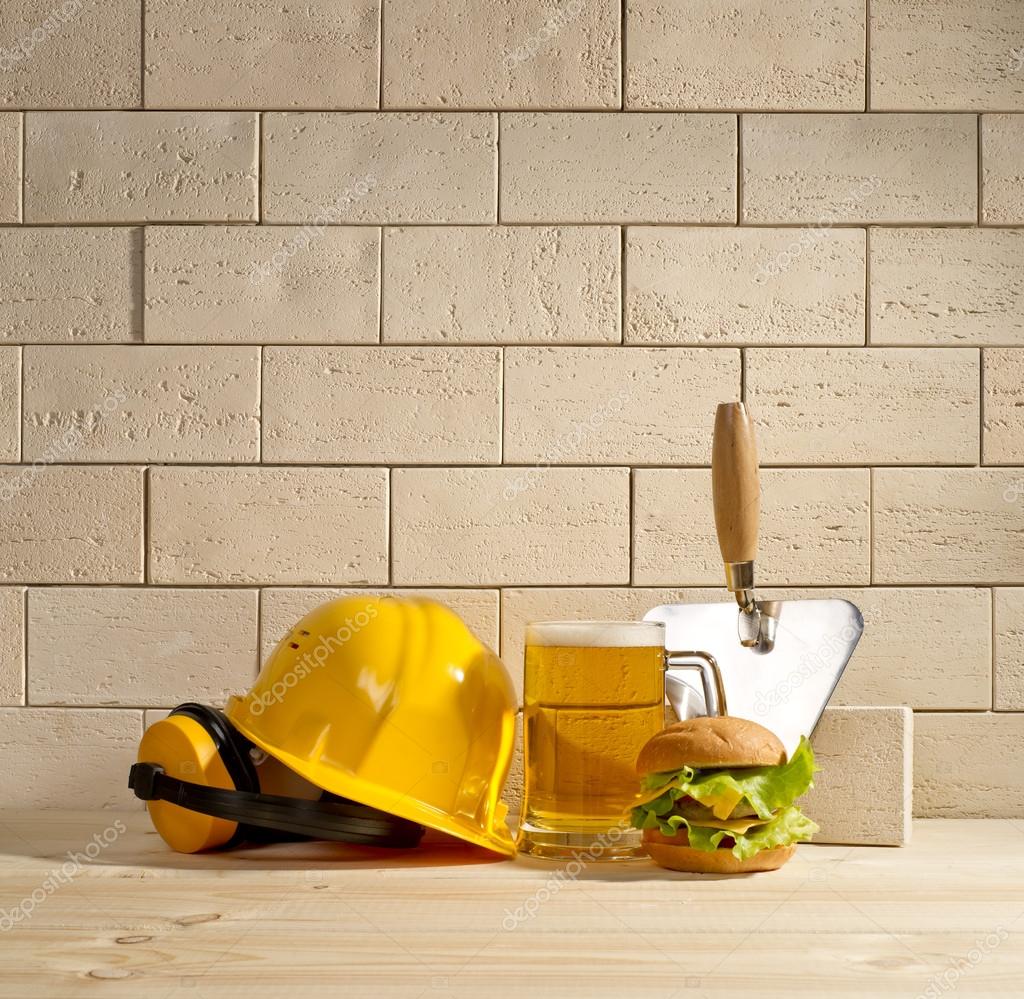 Beer and burger with the helmet and trowel against a brick wall — Stock ...