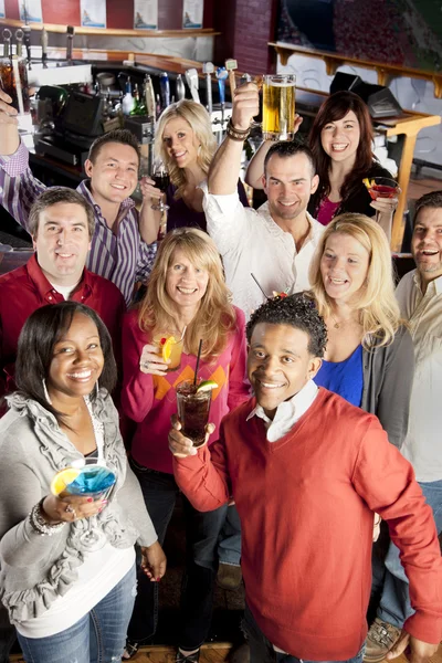 Adults enjoying a night out at a bar holding up drinks Stock Photo by ...