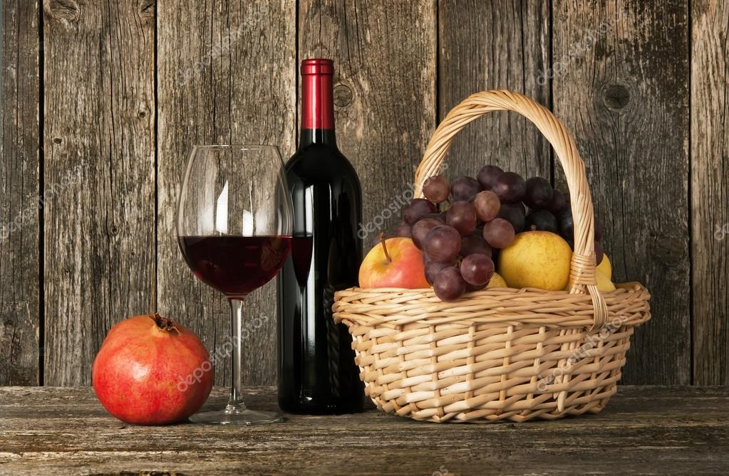 Bodegón. Botella de vino tinto, copa y cesta con fruta 2022