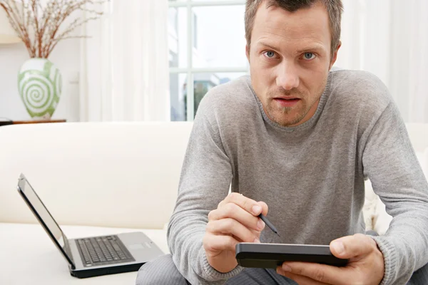 Young entrepreneur man using technology while sitting on a white sofa ...