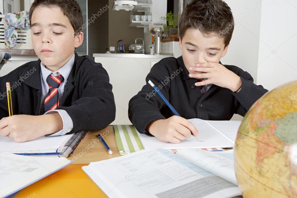Two identical twin brothers doing their homework together on the ...