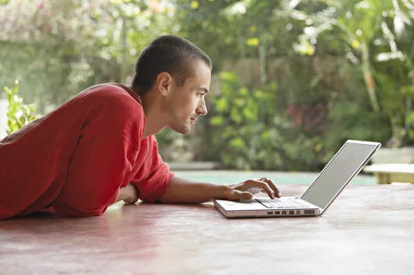 Young man using a laptop computer while laying down - Stock Image ...