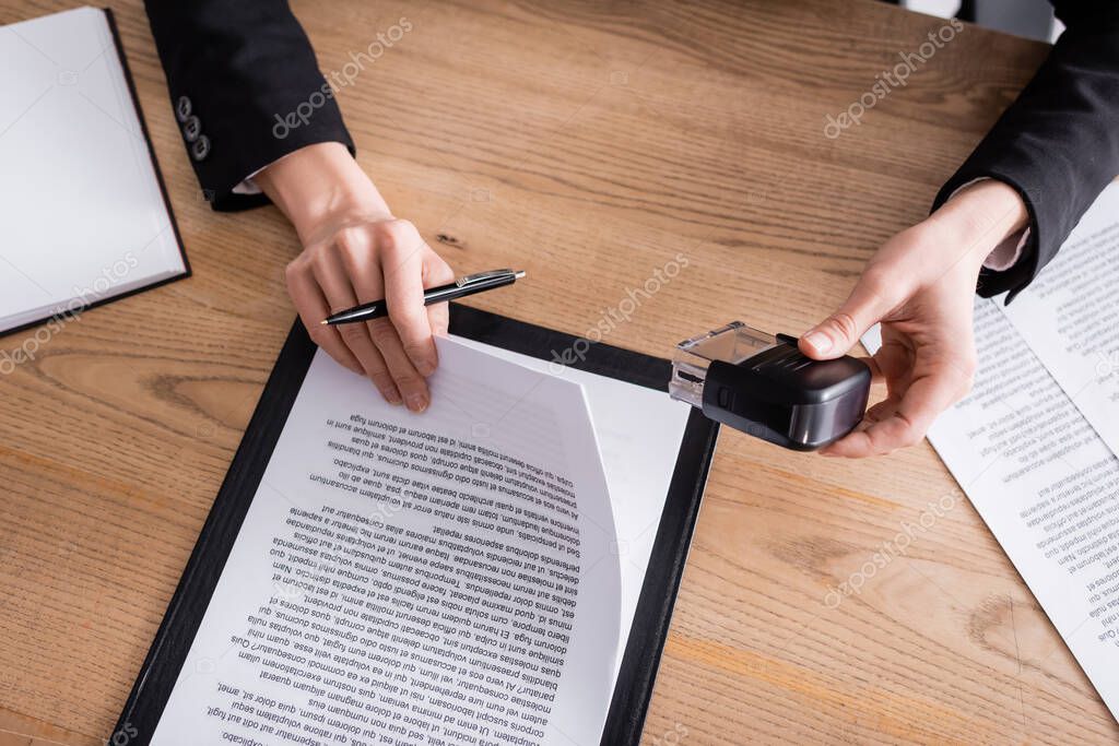 vista parcial del notario que sostiene el sello y la pluma cerca de los ...