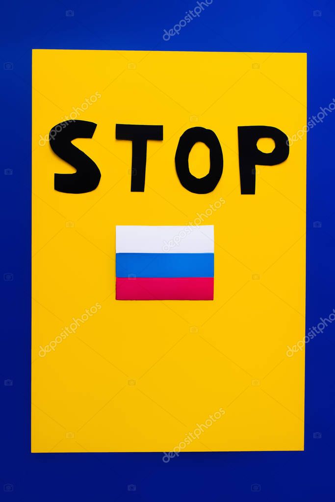 Vista superior de las letras stop y bandera rusa sobre fondo azul y ...