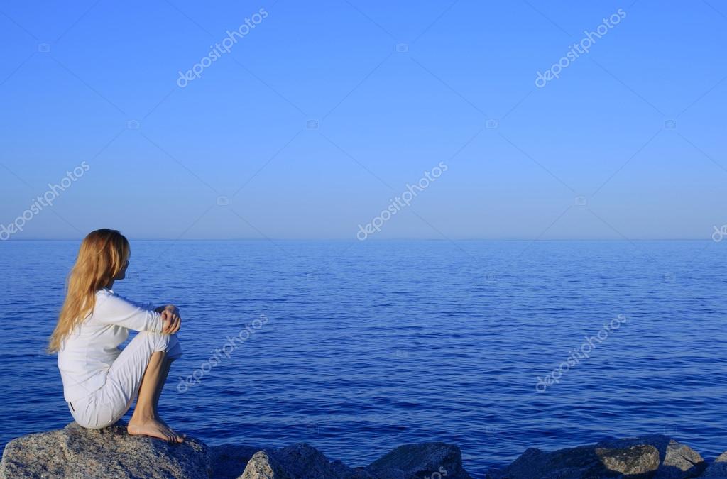 Girl sitting on the rock by the peaceful sea — Stock Photo ...