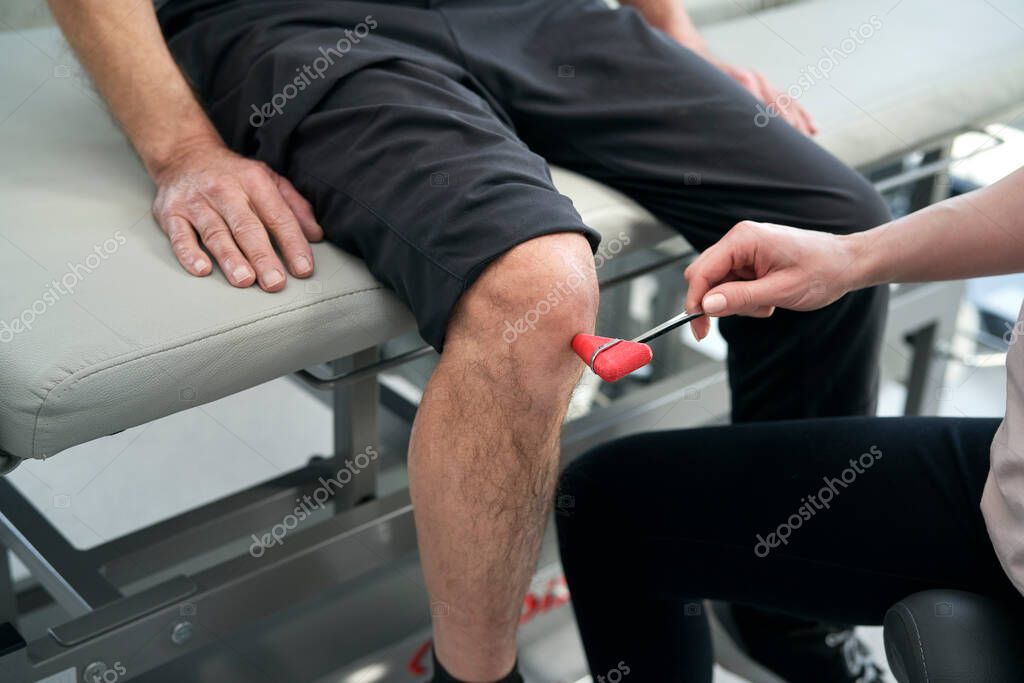 Primer plano de la rodilla del médico de control de martillo de ...