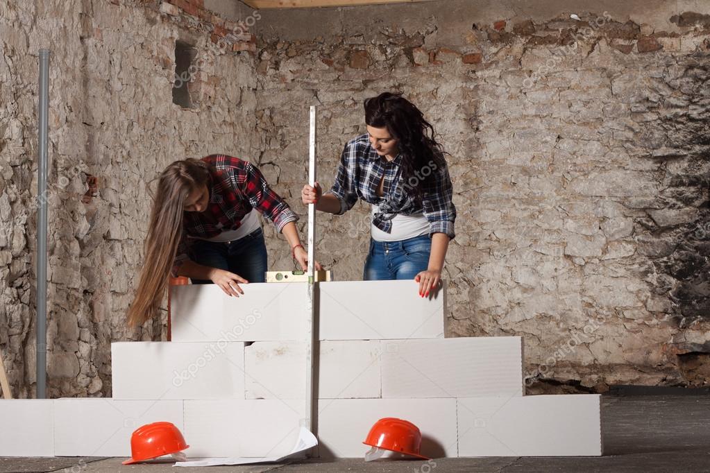 Two young long-haired woman built a new wall from blocks — Stock Photo ...