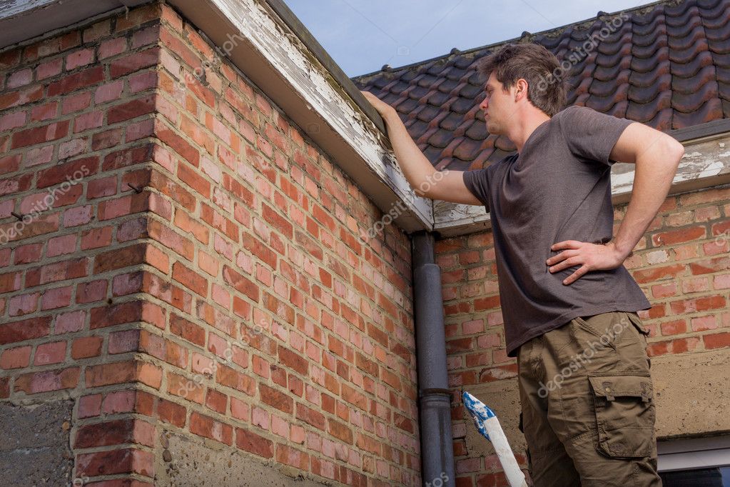 Young man inspecting the roof of an old house Stock Photo by ©paul90 ...