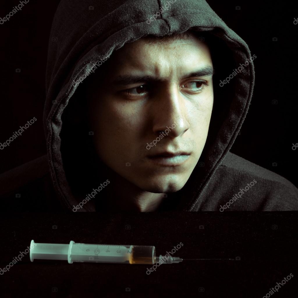 Grunge image of a depressed drug addict looking at a syringe and drugs ...