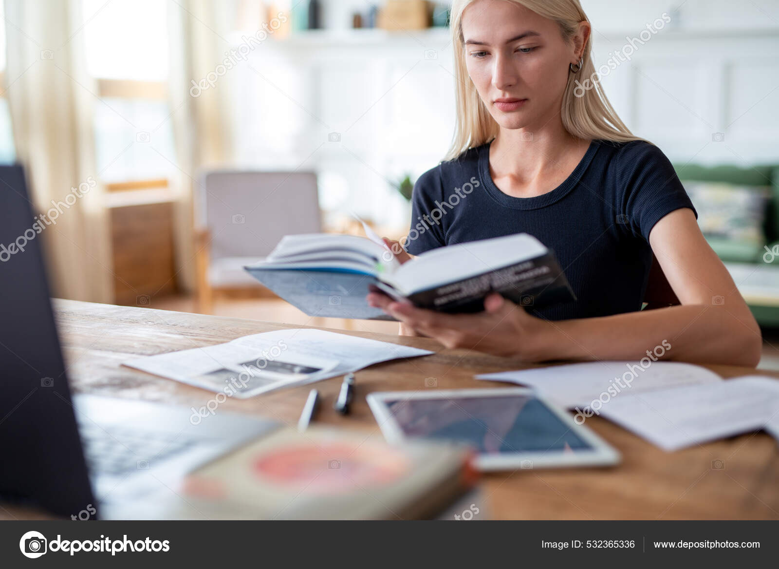 Woman student sitting at table reading book. Stock Photo by ©undrey ...