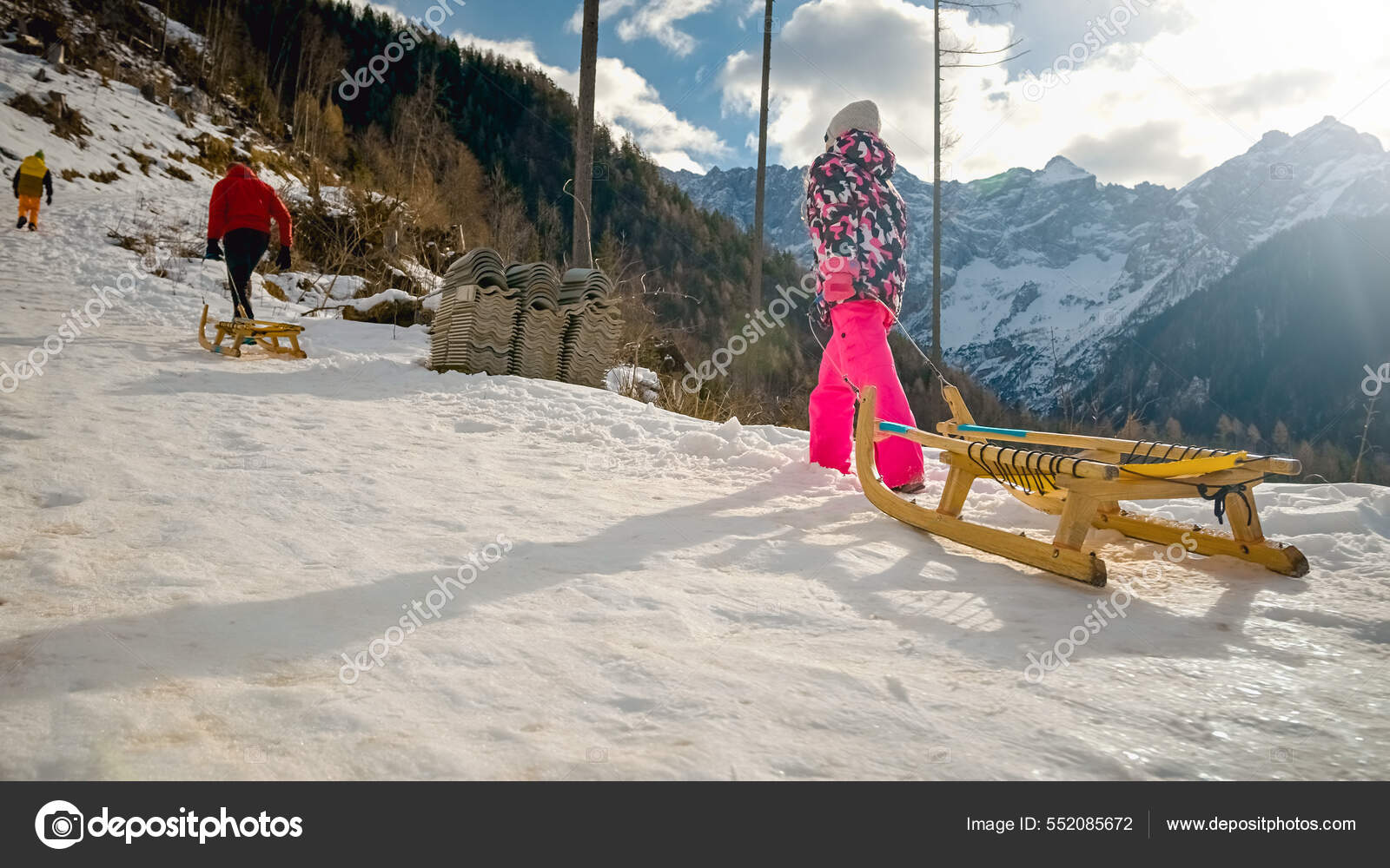 Family pulling sleds on a snowy track in a mountain Stock Photo by ...