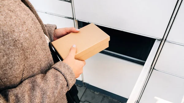 Pickup parcel. Courier box in woman hands at post delivery automat ...