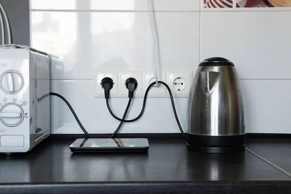 Kitchen and electric kettle on the table near the socket against the ...