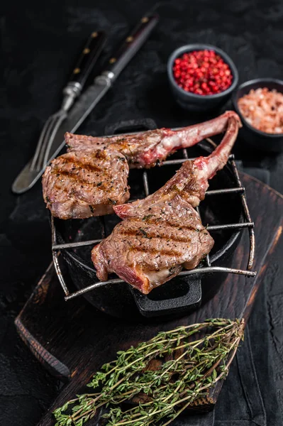 Grilled lamb mutton meat chops steaks on a grill. Black background. Top ...