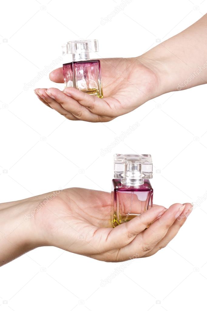 Mano femenina con una botella de perfume sobre fondo blanco 2022