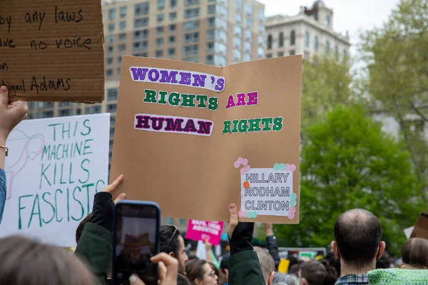 A young Female holding a cardboard sign with the words women's rights ...