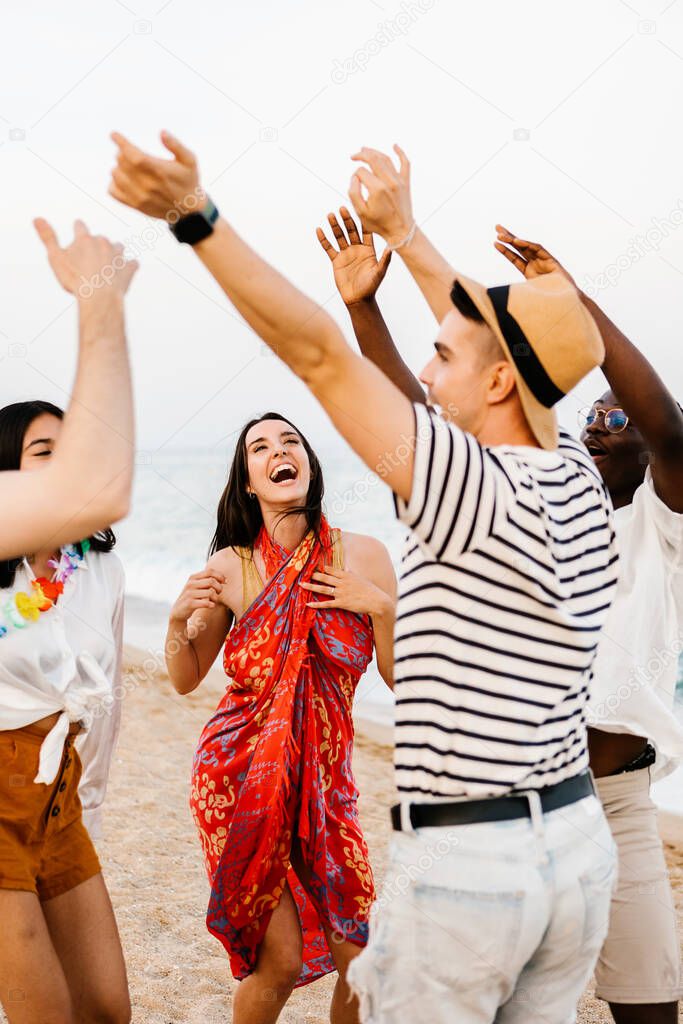 Feliz joven amigos bailando en la fiesta de verano en la playa - tiro vertical de personas ...