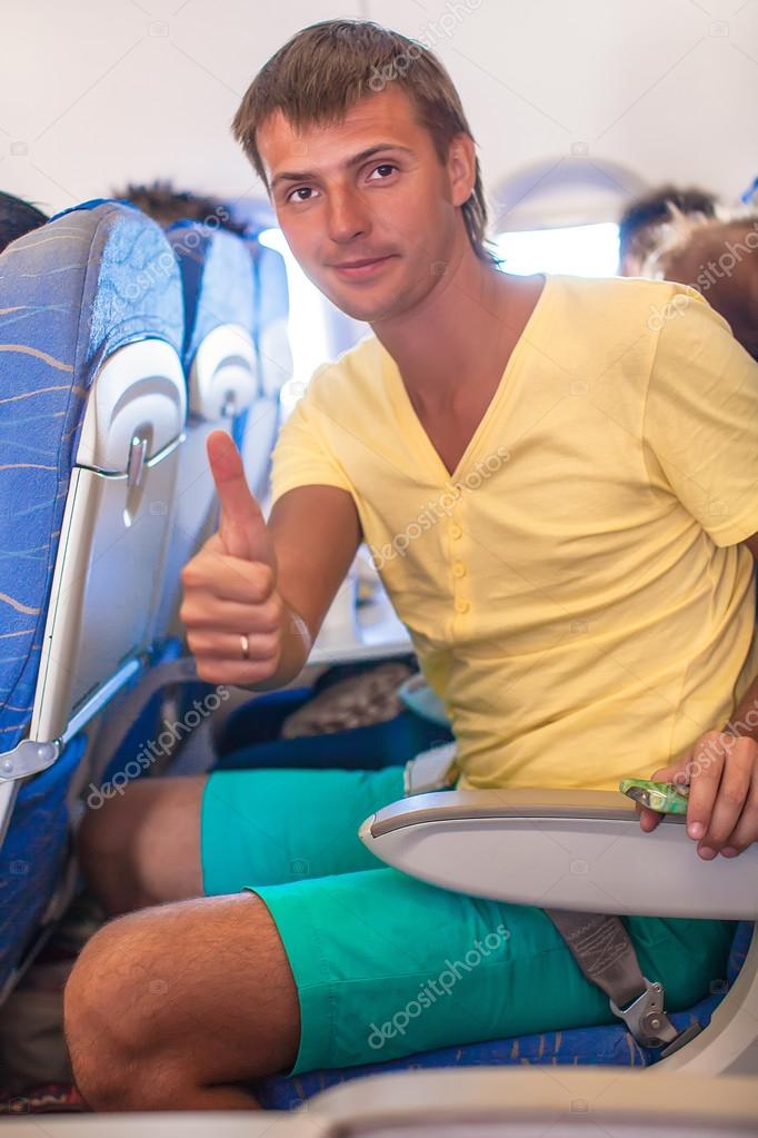 Young man in an airplane during flight showing thums up — Stock Photo ...