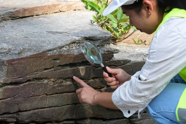 Asian female geologist researcher analyzing rocks with a magnifying ...