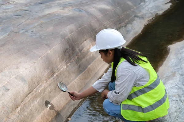 Asian female geologist researcher analyzing rocks with a magnifying ...