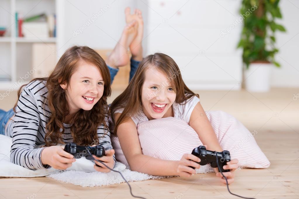 Two young girls happily playing video games — Stock Photo © racorn ...