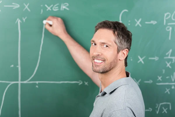 Teacher Holding Paper While Writing On Chalkboard Stock Photo by ...