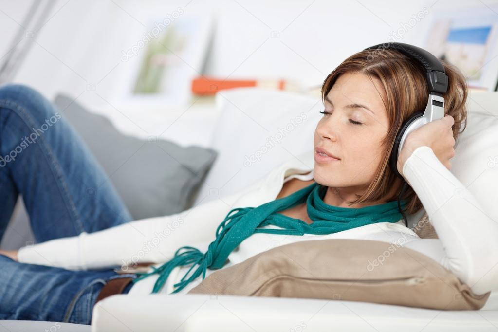 Woman relaxing on a sofa listening to music Stock Photo by ©racorn 27135661