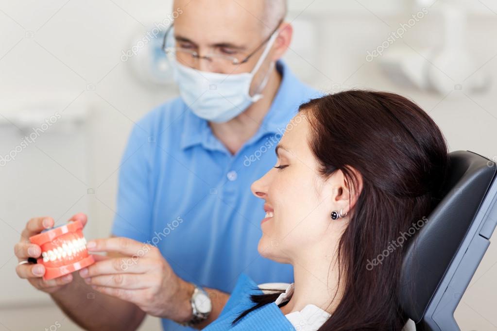 Dentista masculino explicando dientes artificiales 2022