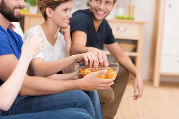 Friends eating snacks while watching television - Stock Image - Everypixel