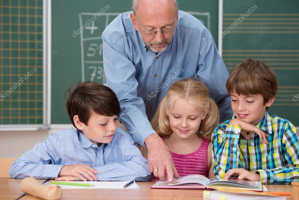 Profesor explicando libro de texto a sus estudiantes: fotografía de ...
