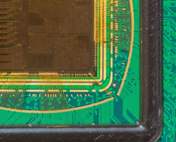 Open computer chip with gold wire connections compared to a needle ...