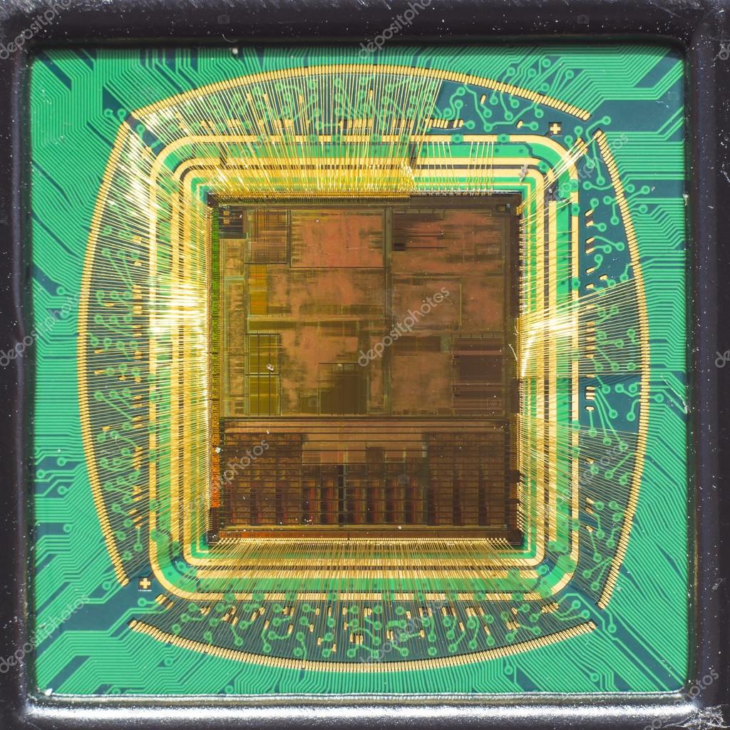 Open computer chip with gold wire connections compared to a needle ...