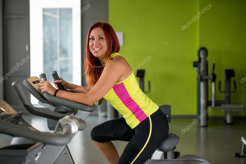 Happy woman working out on a gym cycle — Stock Photo © ibrak #29701779
