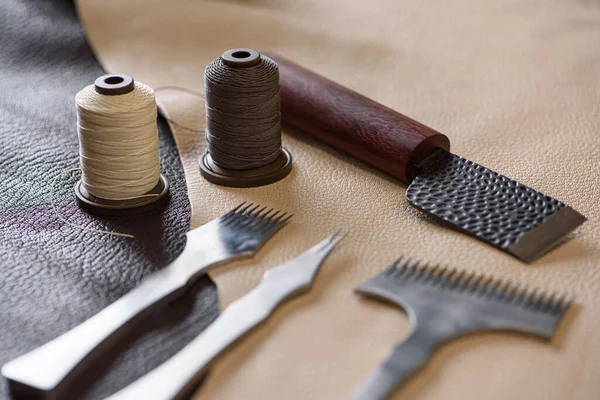 Shoemaker's tools laying on piece of beige and brown genuine leather in ...