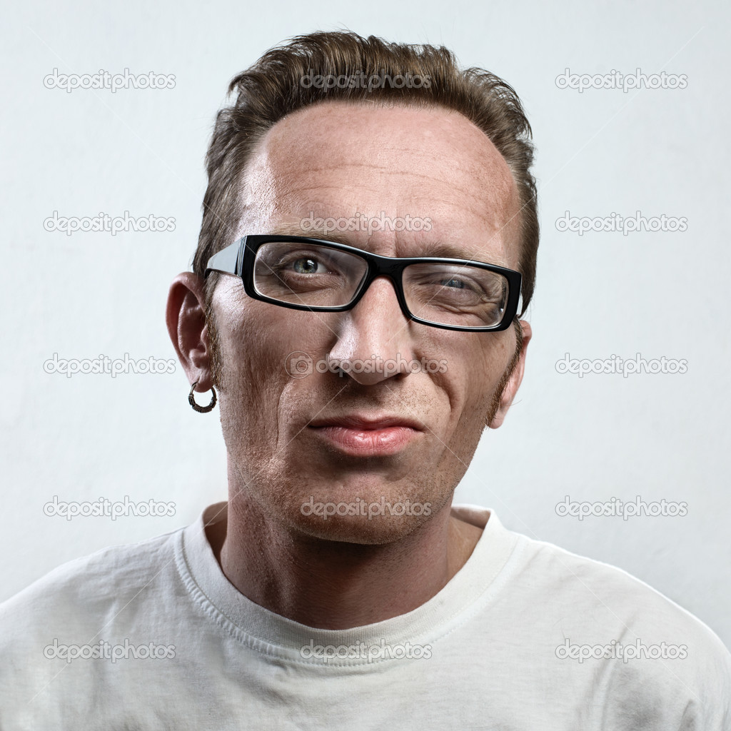 Portrait unsatisfied man with an earring in a white t-shirt on light ...