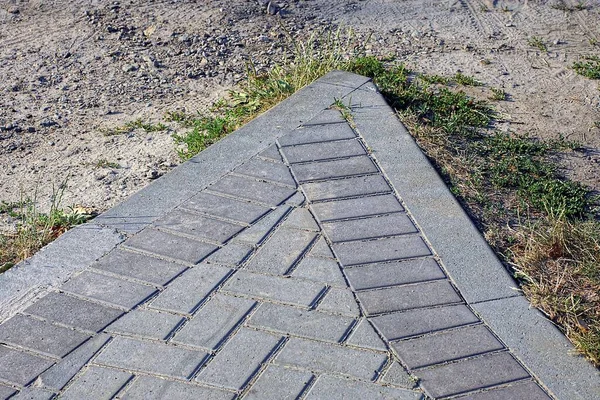 part of an alley made of gray pavement with an acute angle on the ...