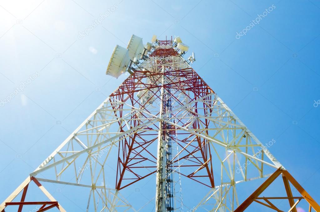 Communications tower showing sun flare with antennas against blu Stock ...